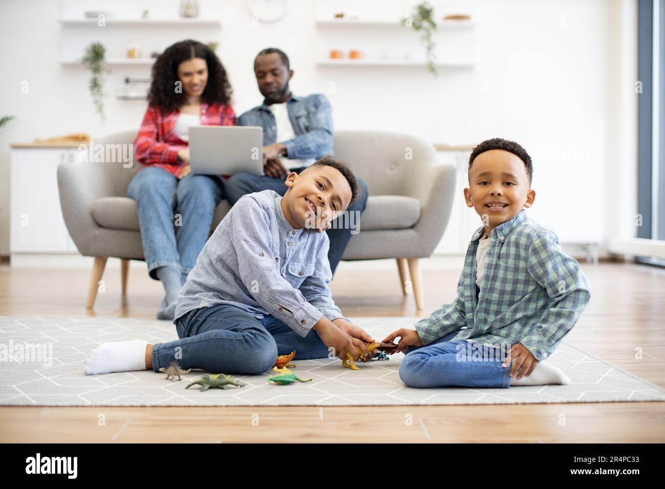 Full length portrait of two multicultural boys posing on carpet while ...