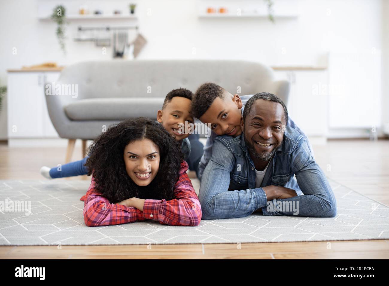 Cheerful multicultural mom and dad carrying happy children on their ...