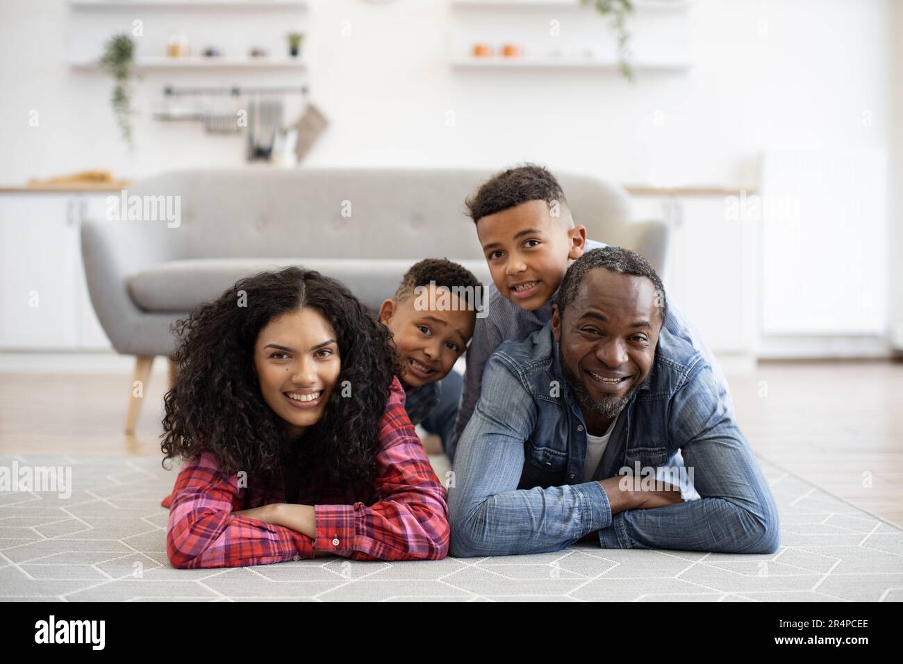 Cheerful multicultural mom and dad carrying happy children on their ...