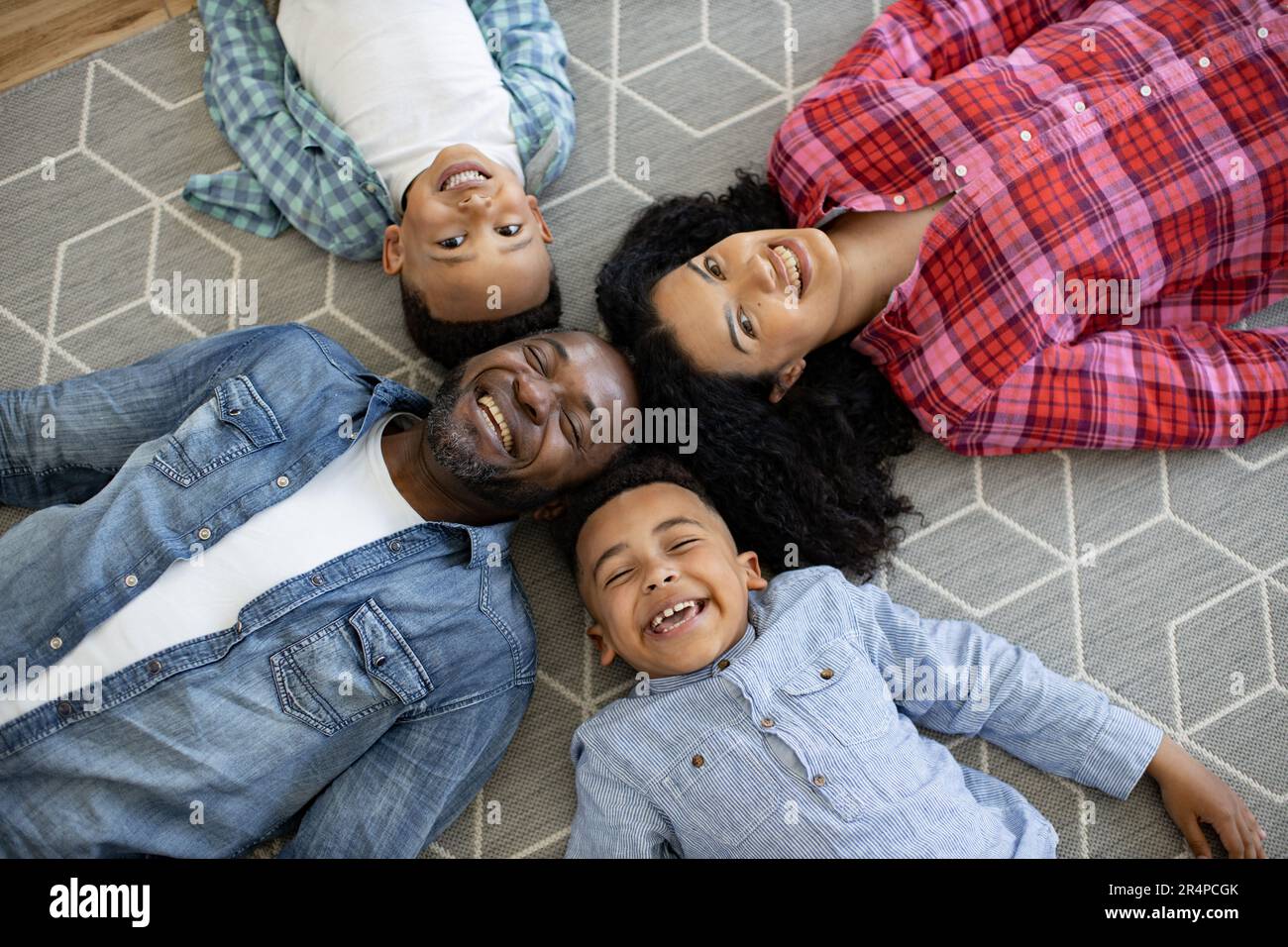 Top view of multiethnic four-person family lying in circle with heads ...