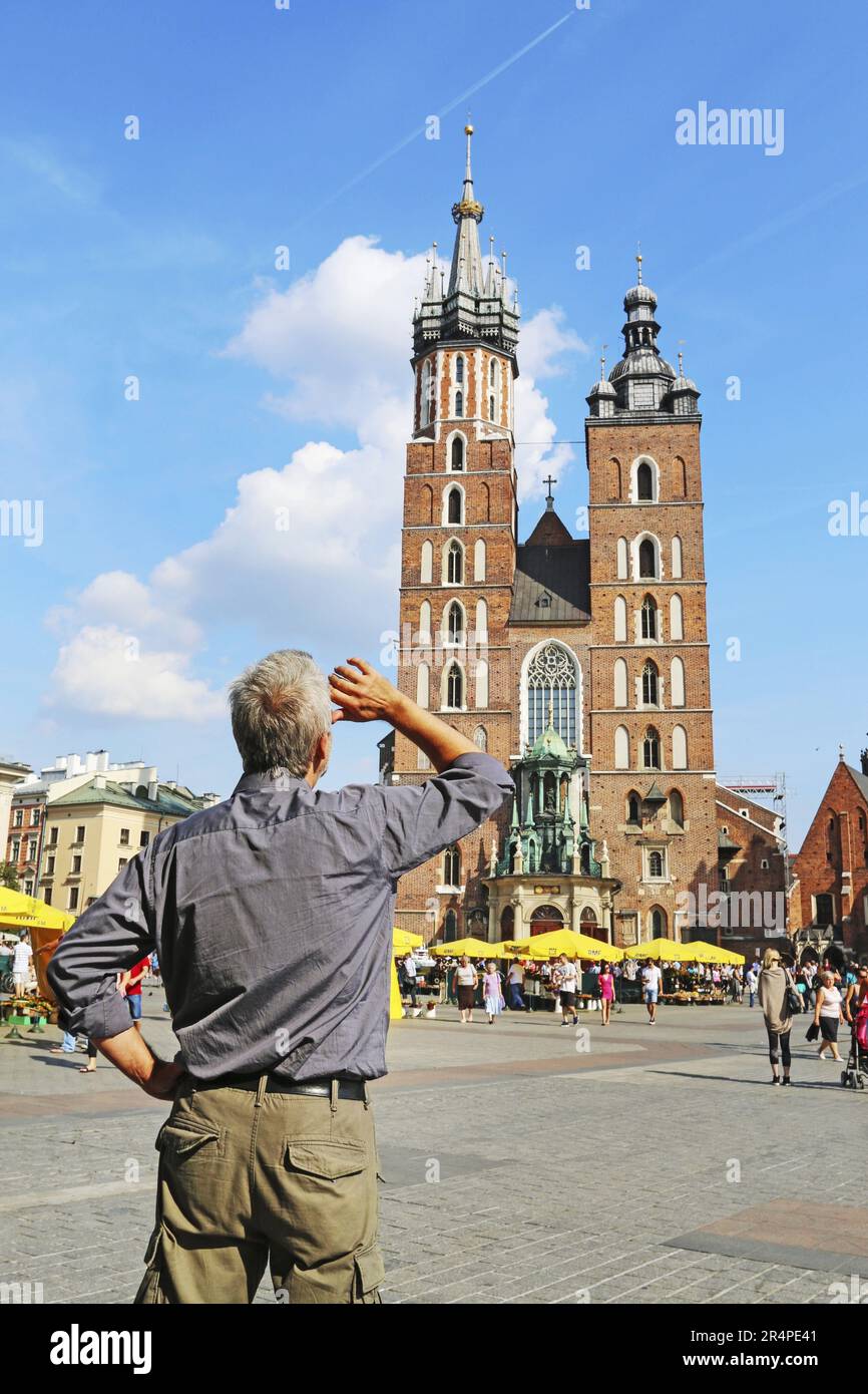 Tourist looks at the Mariacki church, Church of Our Lady Assumed into ...