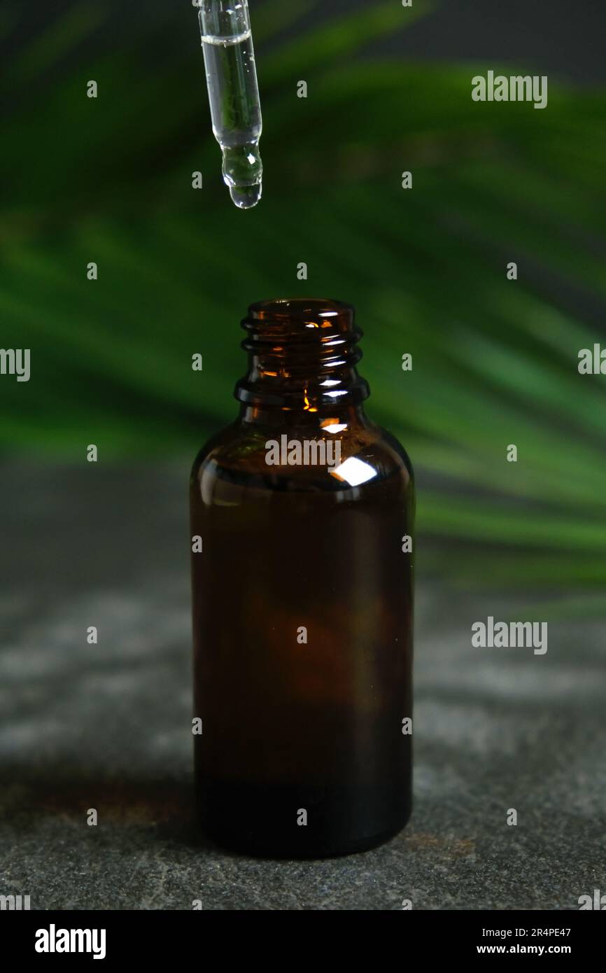 Drop of clear liquid, oil, serum or tincture dripping from pipette in ...