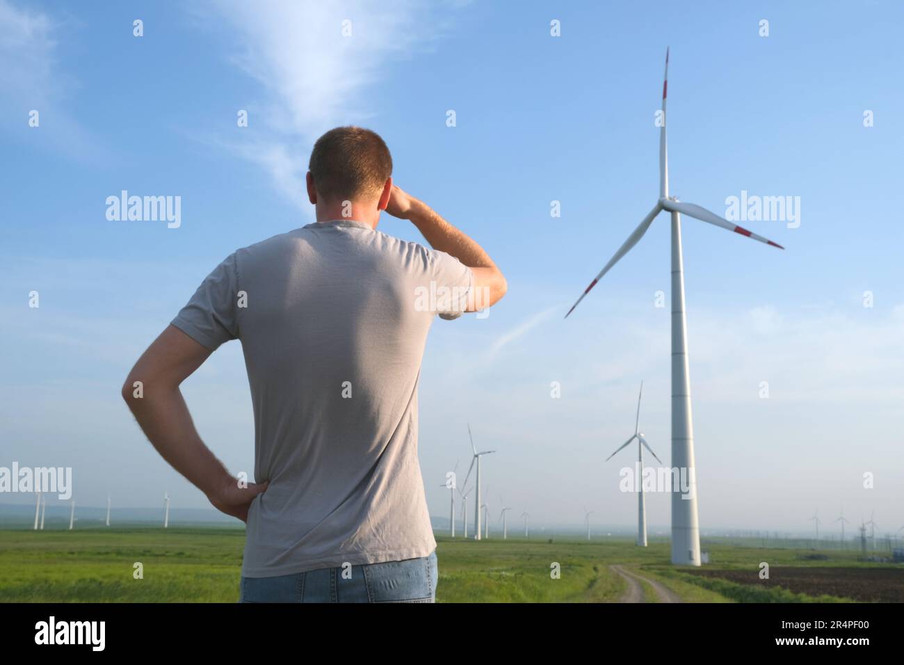 The man stands with his back and looks at the wind turbine. Wind Energy ...