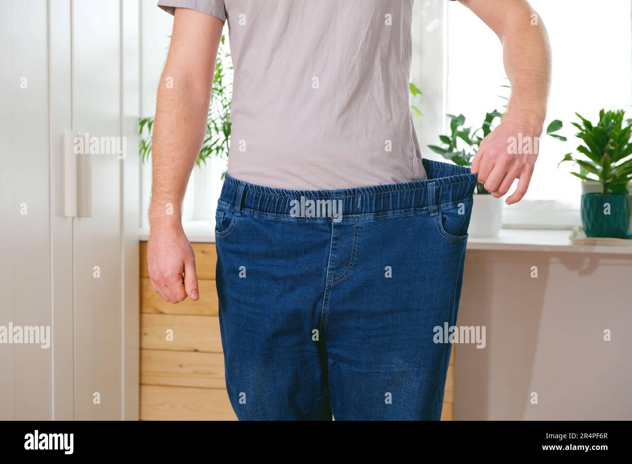 The guy is trying on big jeans after losing weight. Man in oversized ...