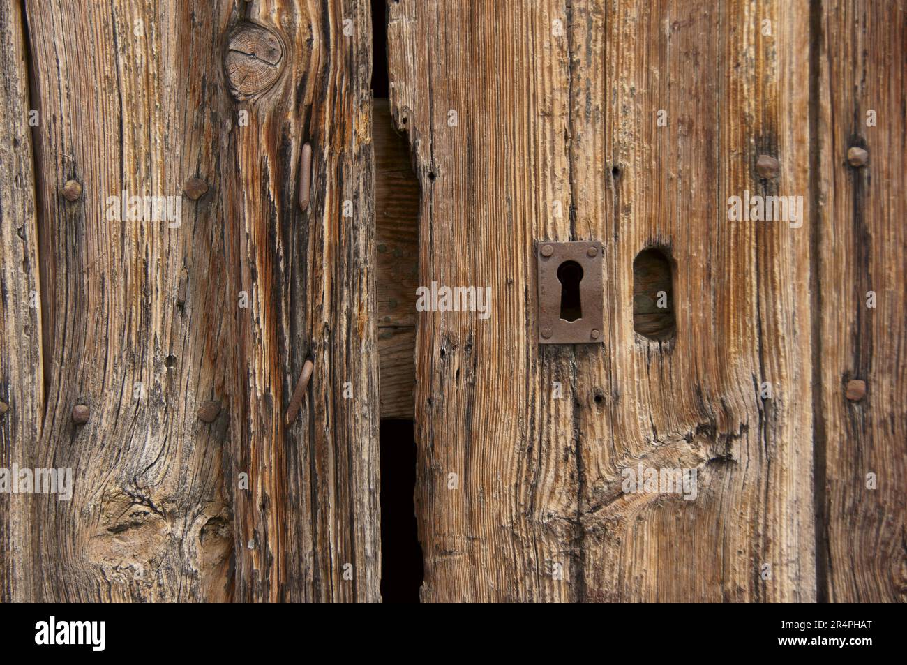 Close up an ancient door with hole where old lock was and the new lock ...