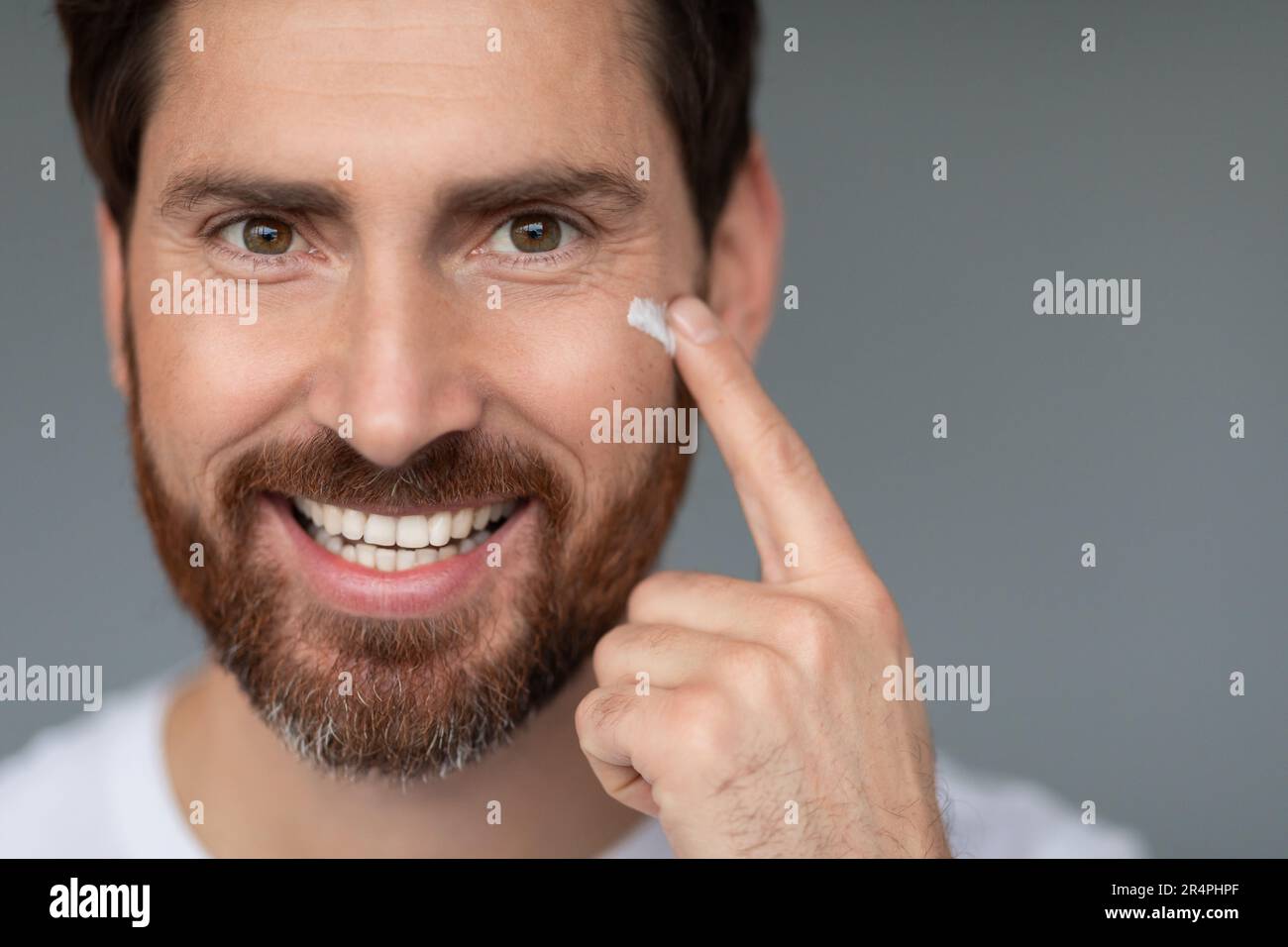 Meticulous self-care. Handsome middle aged man applying anti-aging ...