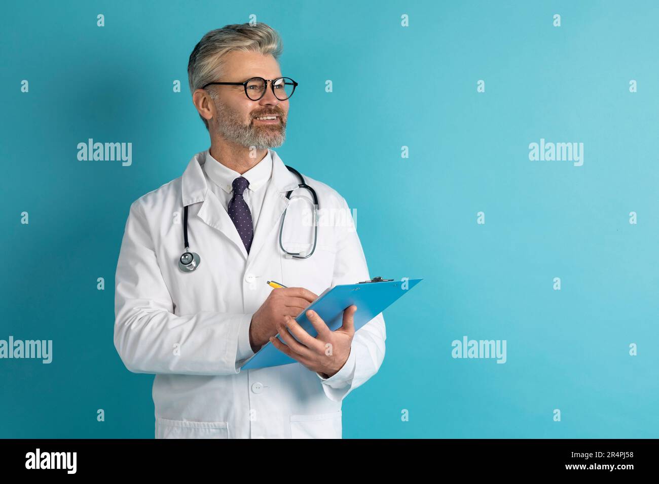 Handsome middle aged doctor taking anamnesis, blue background Stock ...