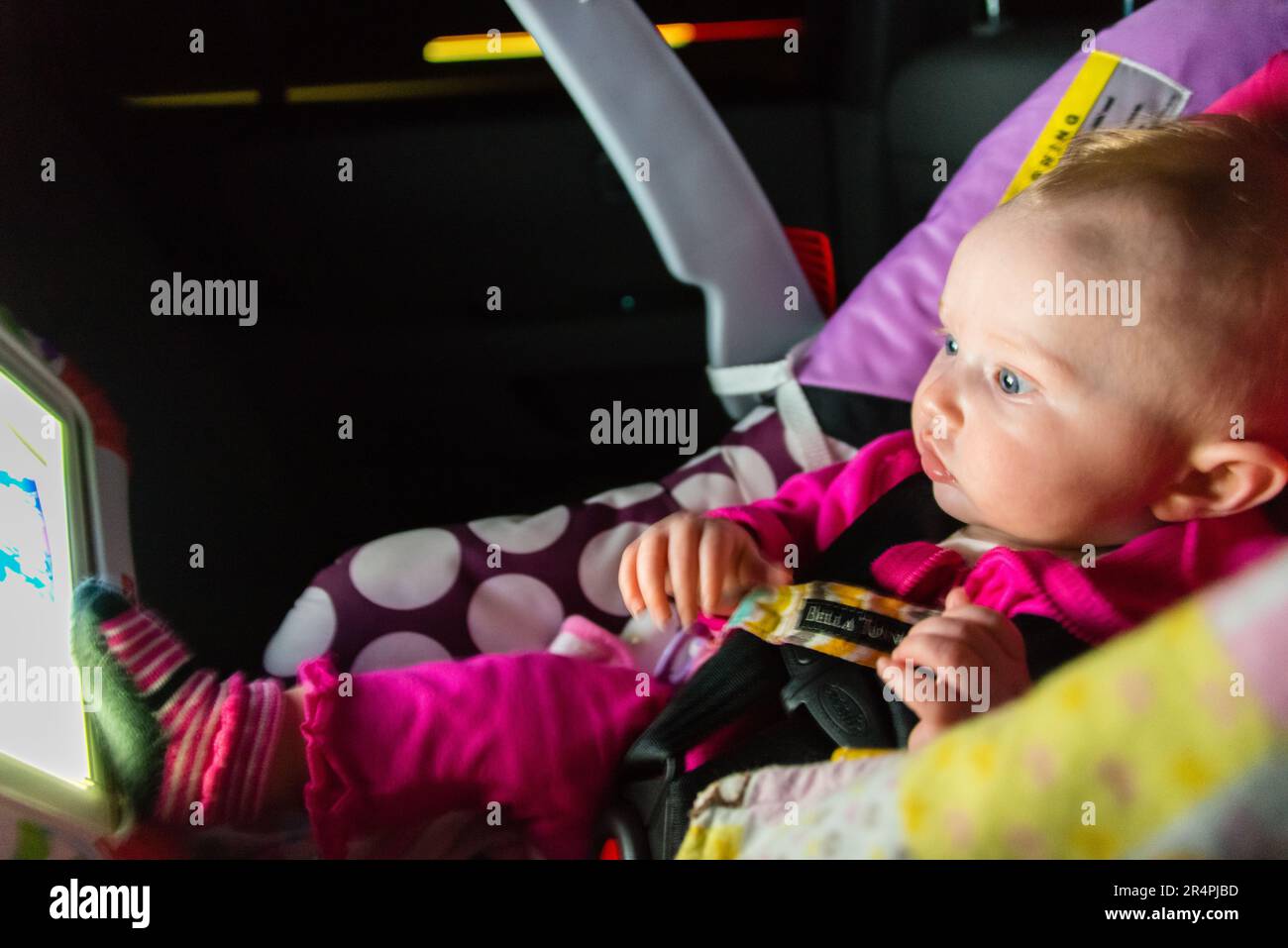 Five- month-old baby watching an Apple iPad from a car seat while ...