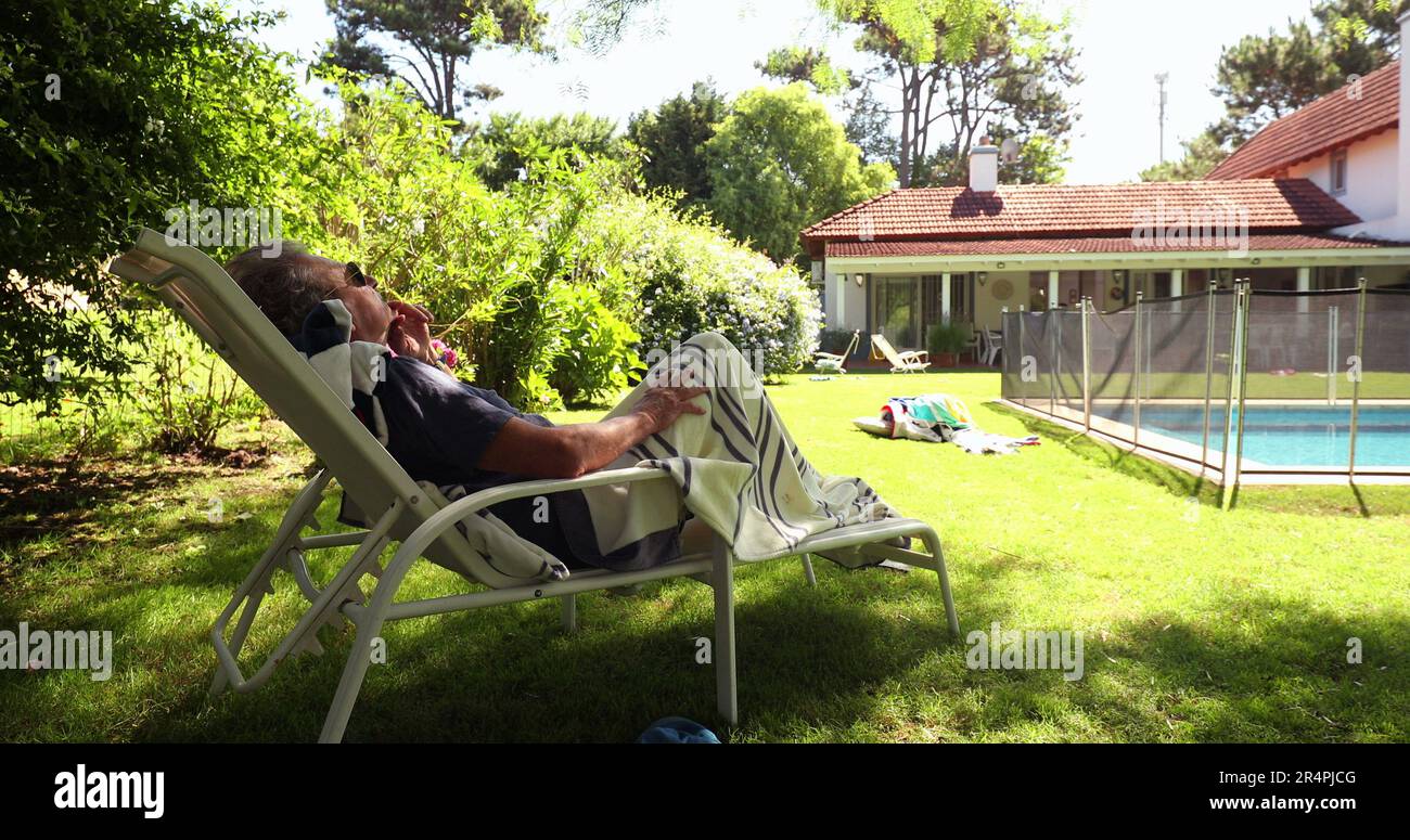 Senior pensive man resting outside in backyard home. Older retired man ...