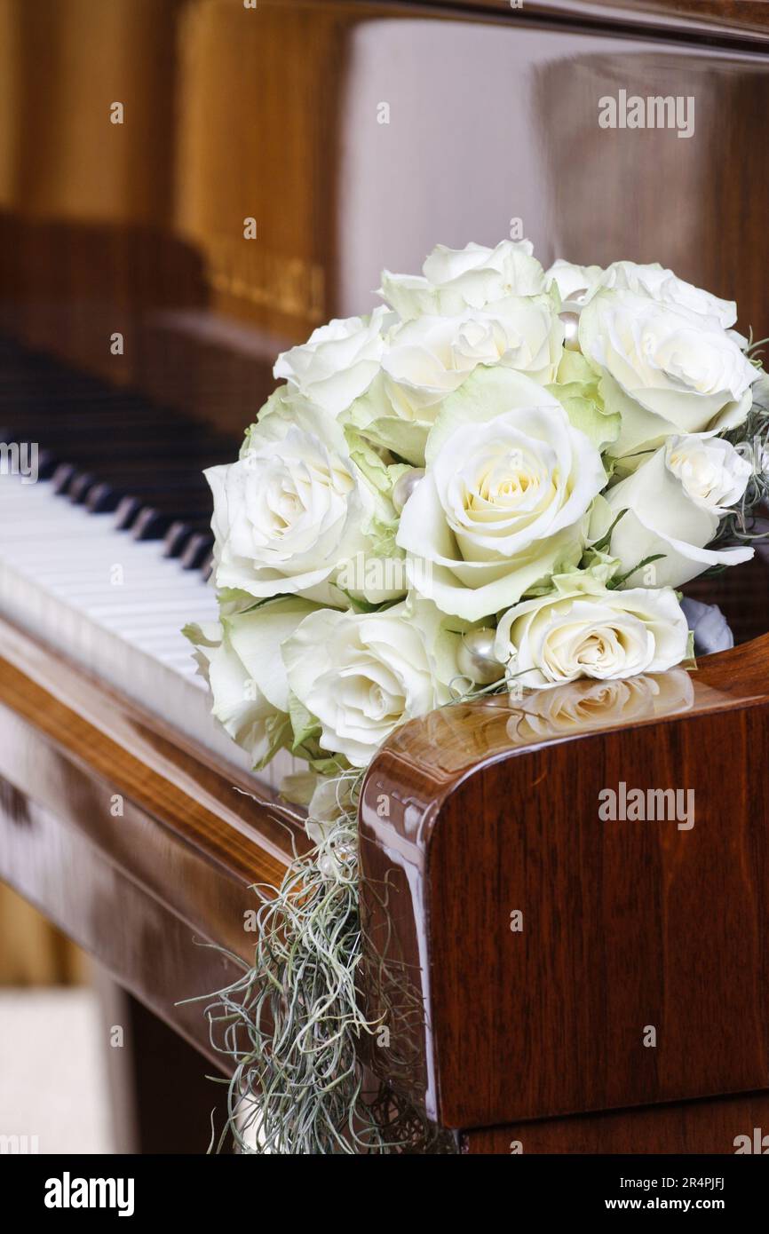 Wedding bouquet of white roses lying on the piano keys. Party decor ...