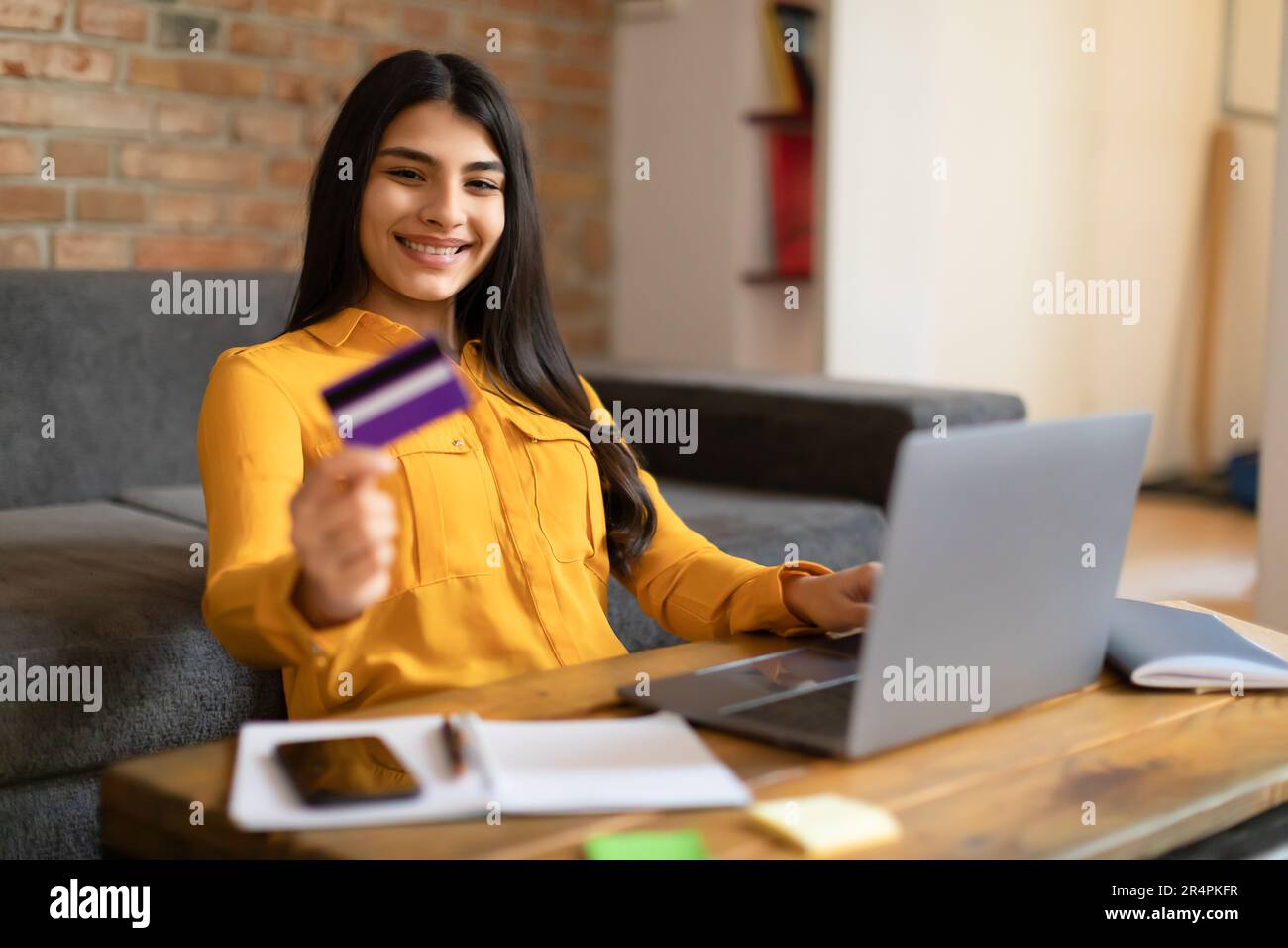 Joyful spanish lady shopping online at home, using credit card and ...
