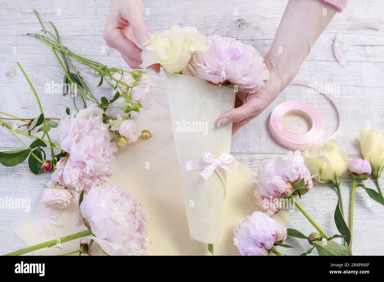 Florist at work: woman shows who to arrange flowers inside a paper ...