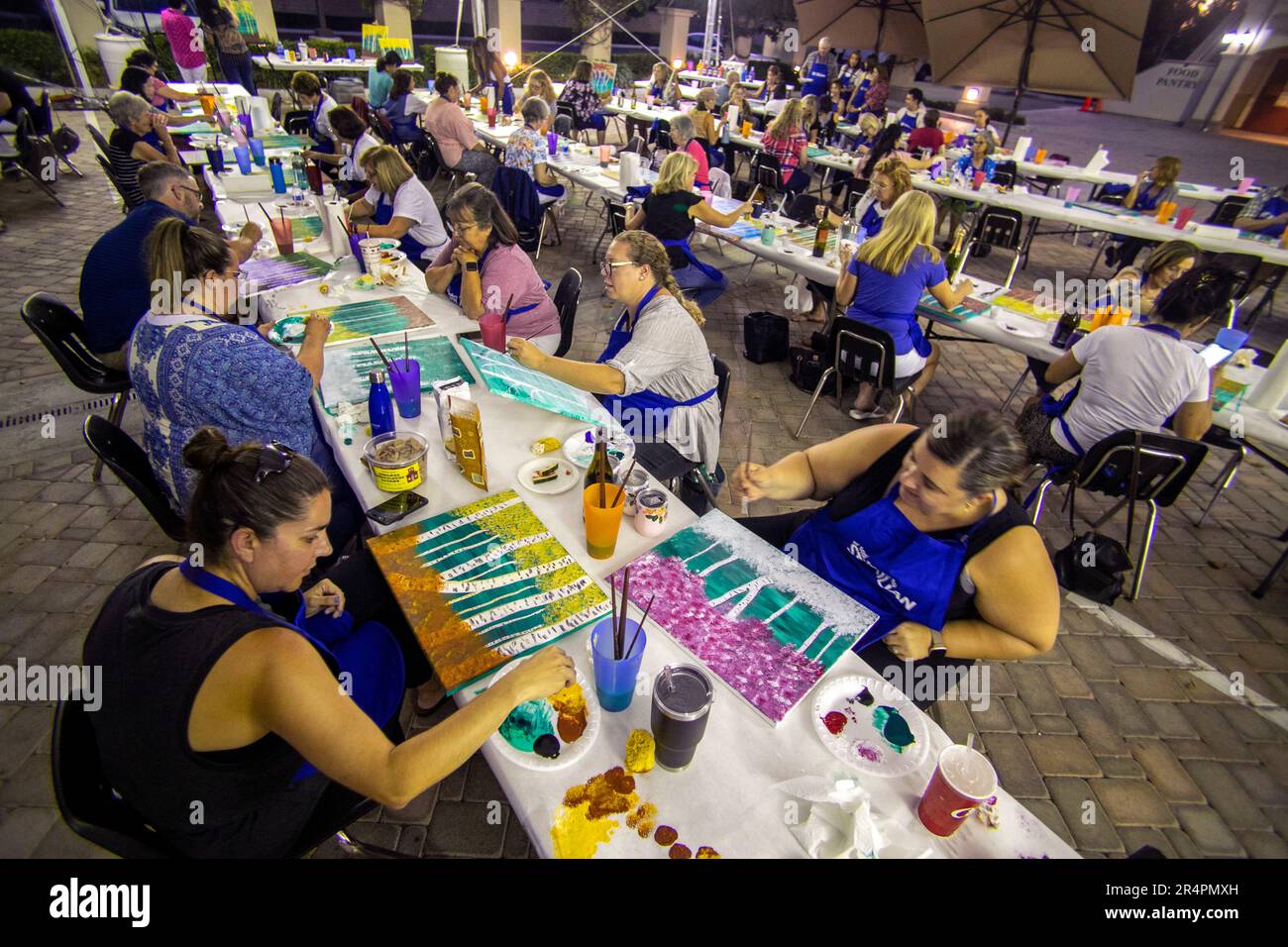 Men and women participate in an amateur outdoor painting art project at ...