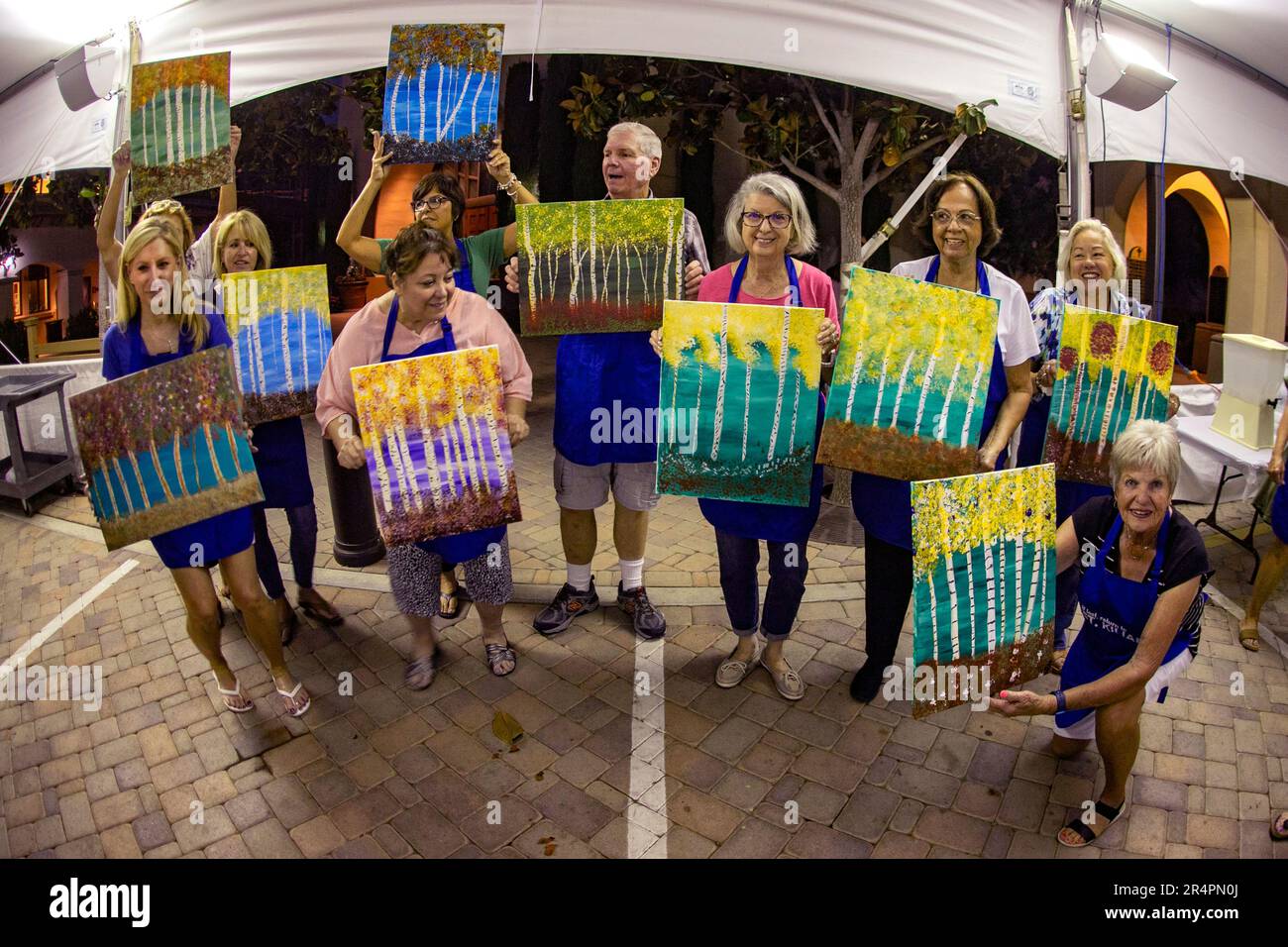 Men and women participate in an amateur outdoor painting art project at ...