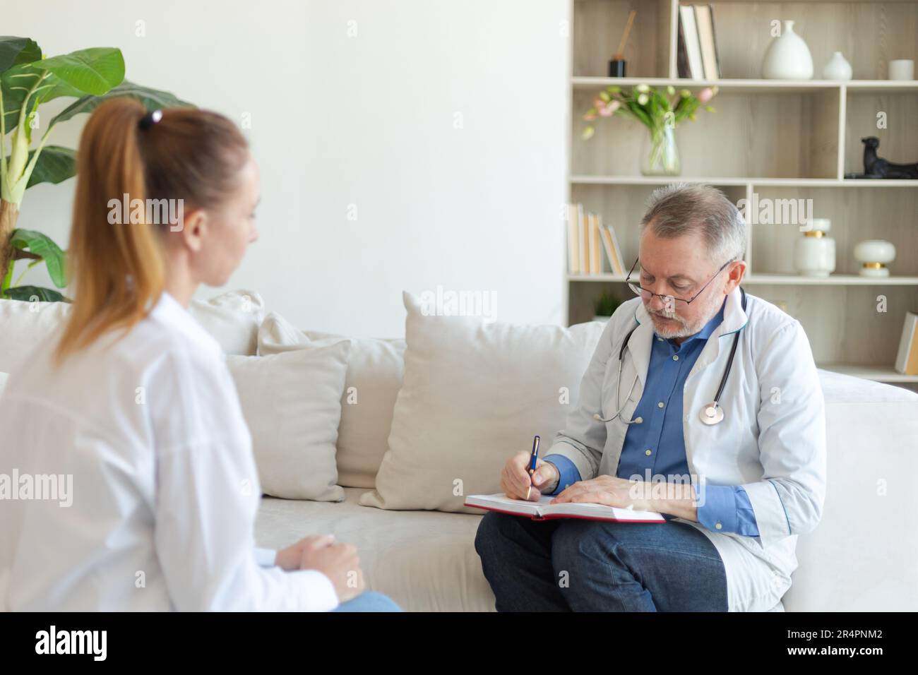 Senior man doctor examining yound woman in doctor office or at home ...