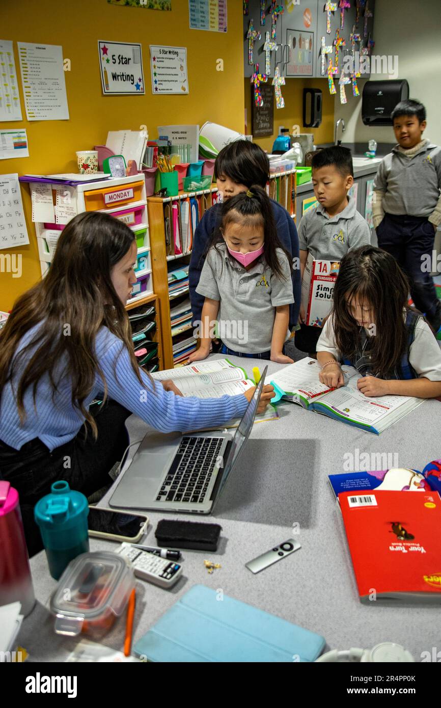 Young multiracial students line up for workbook advice from their first ...