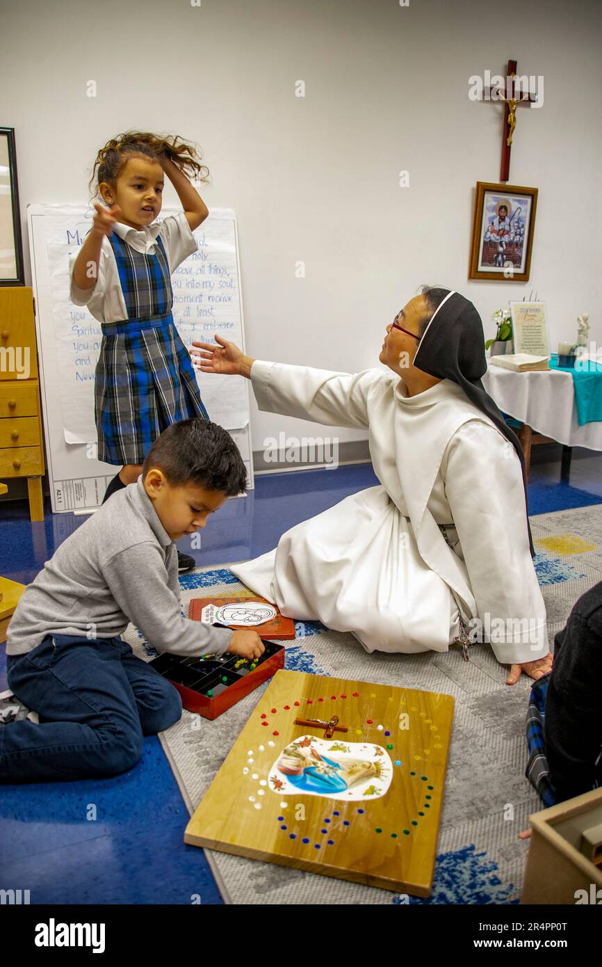 A uniformed kindergarten girl gets advice from a Hispanic nun at a ...