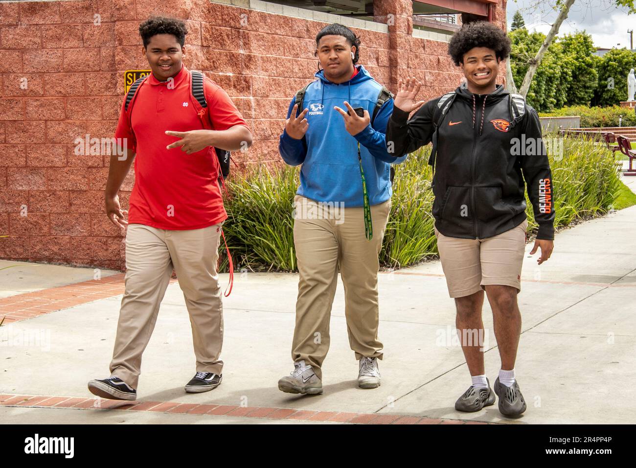 Three African American students at a Southern California Catholic high school use hand gestures ...
