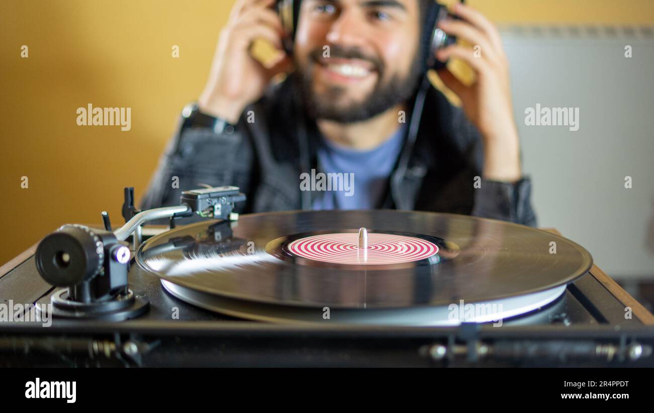 Young man using headphones while playing a vinyl record on a vintage ...