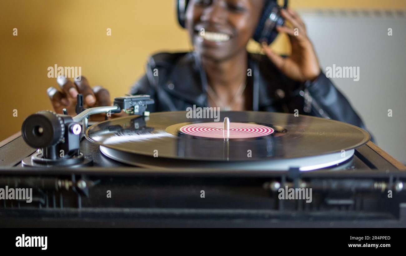 young woman wearing a leather jacket using headphones while playing a ...