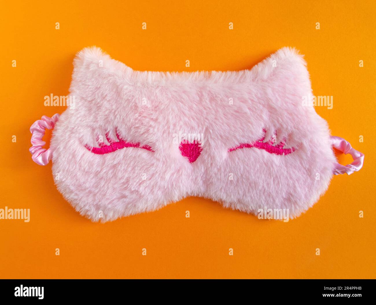 Pastel pink fluffy fur sleep mask with small ears on pastel yellow ...