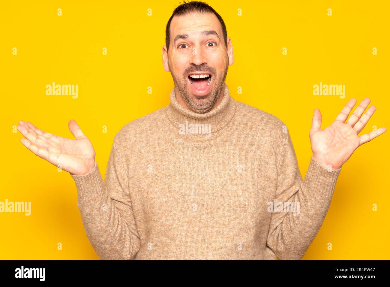 Funny smiling man in beige sweater showing palms up, unexpected ...