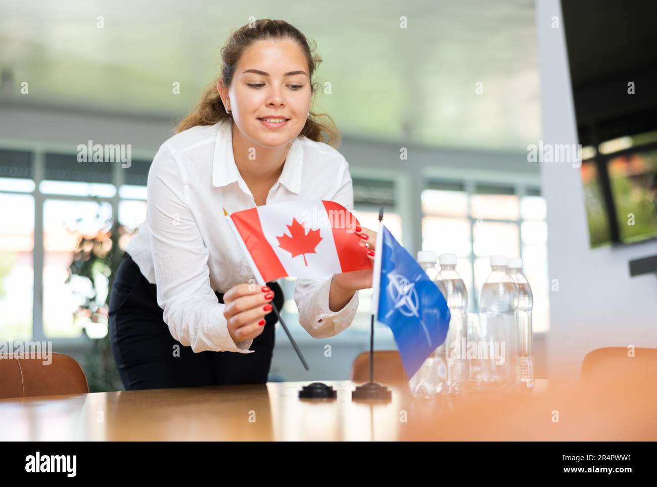 Female secretary places flags of the NATO (OTAN) and Canada on the ...