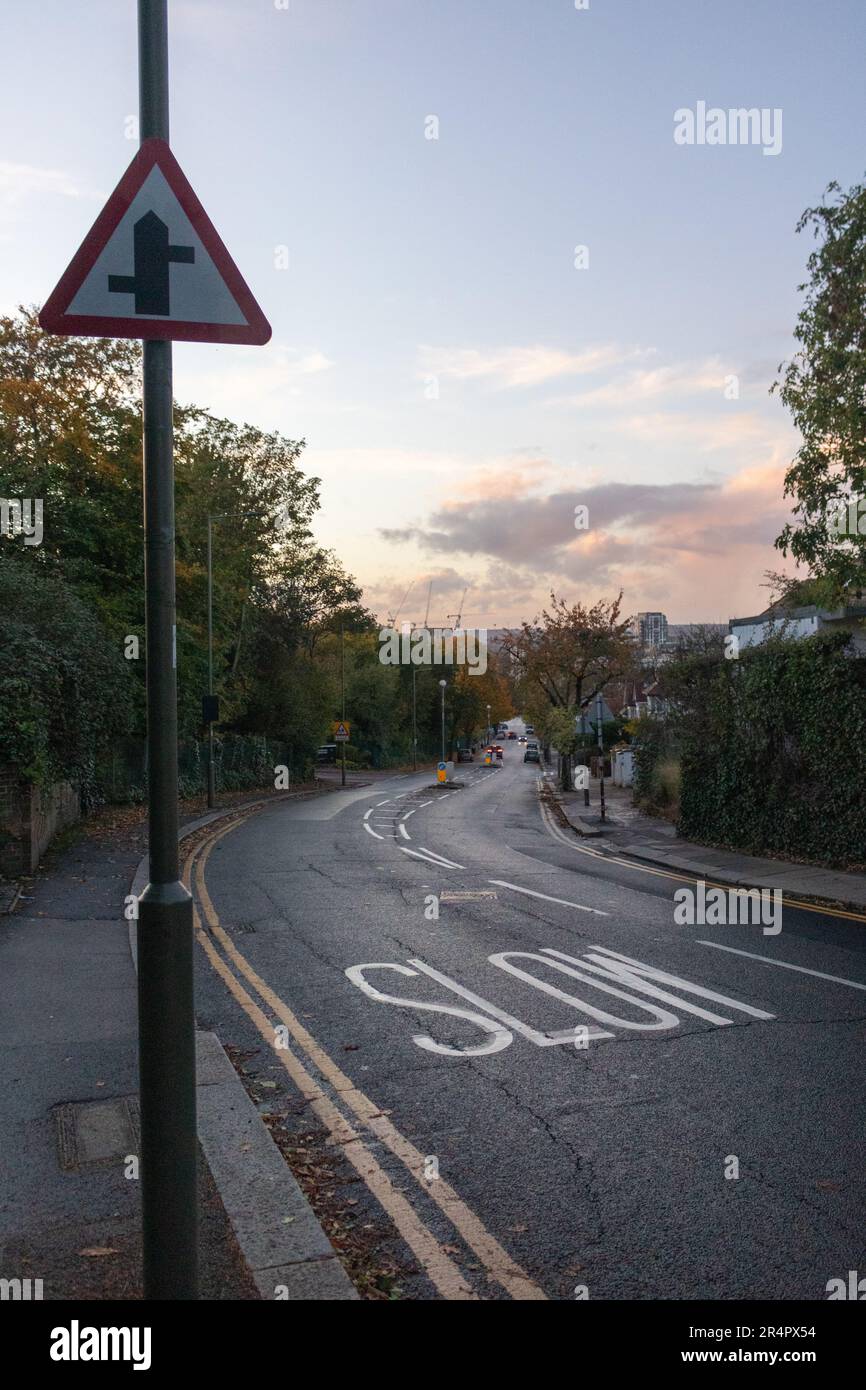 Curved road going down hill with road marking SLOW. Blue sky and sunset ...
