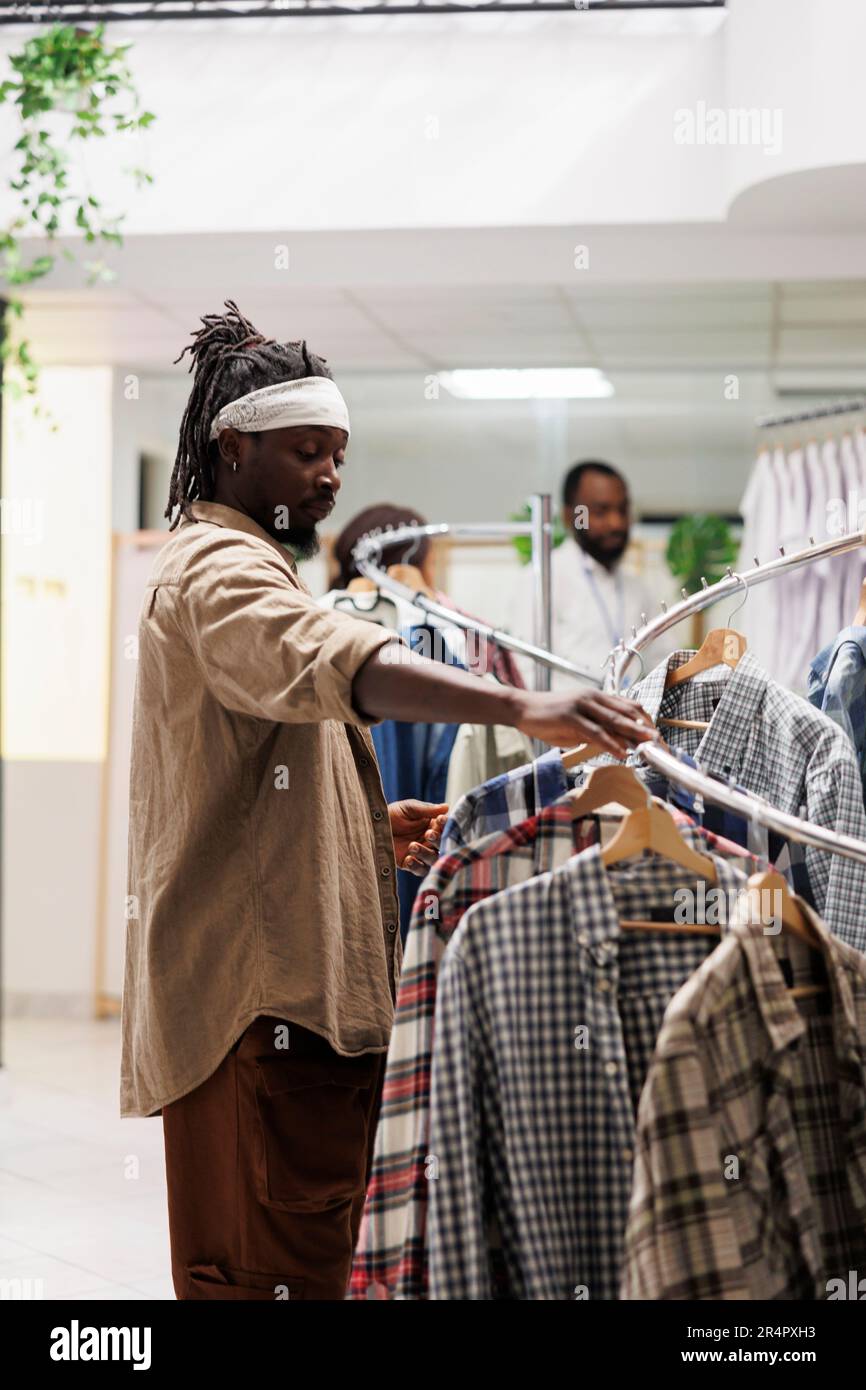 Man searching for trendy outfit in clothing store Stock Photo - Alamy