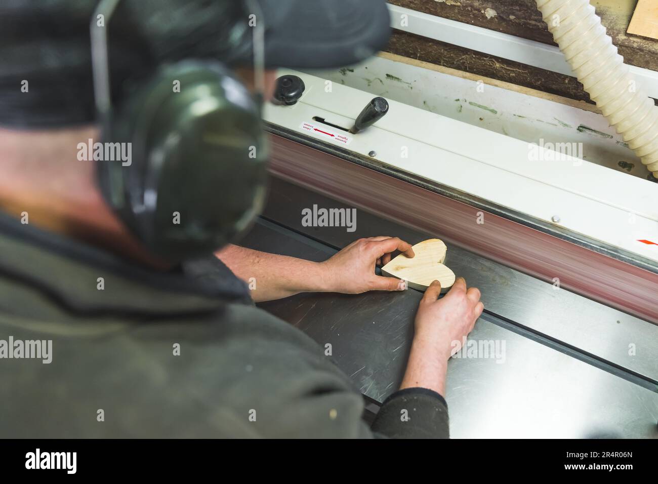 Hands of a carpenter shaping a piece of wood using a grinding machine ...