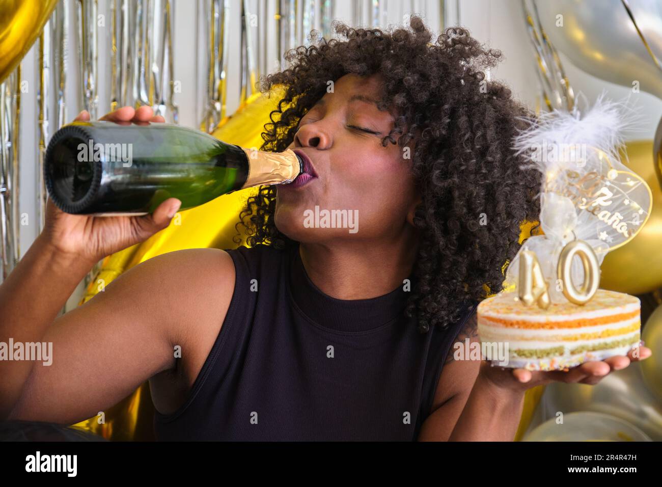 African woman drinking champagne from bottle celebrating her 40 ...