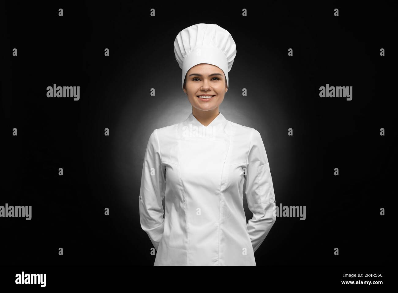 Happy female chef wearing uniform and cap on black background Stock ...