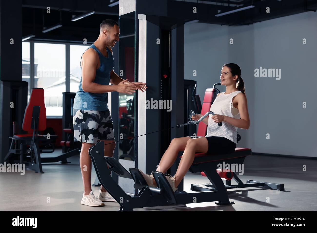 Happy trainer explaining woman how to do exercise properly in modern ...