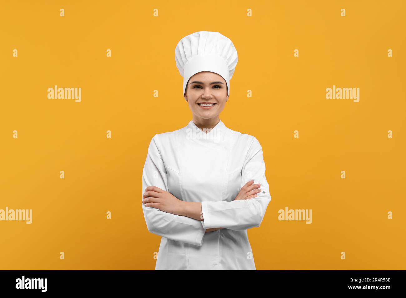 Happy female chef wearing uniform and cap on orange background Stock ...