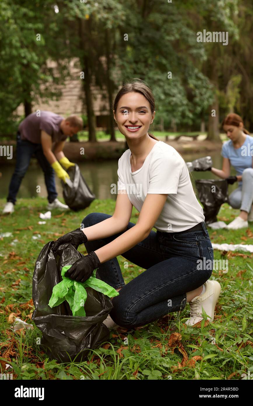 Woman with plastic bag collecting garbage in park Stock Photo - Alamy