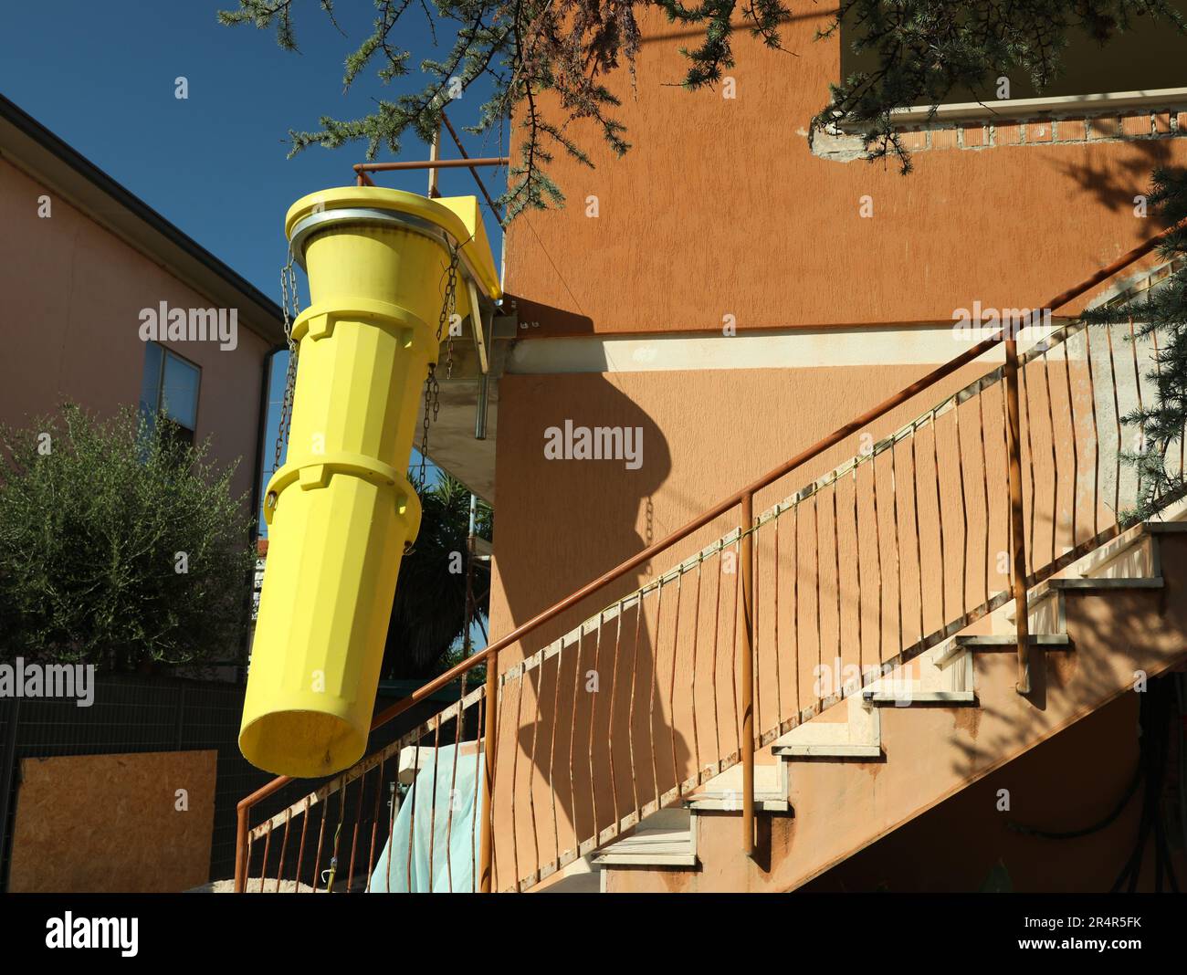 Building with yellow rubble chute outdoors on sunny day Stock Photo - Alamy