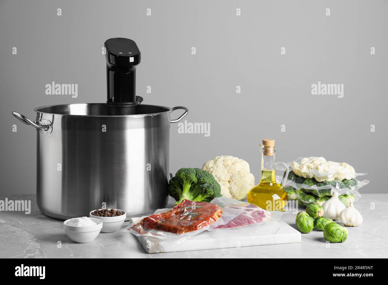 Thermal immersion circulator in pot and ingredients on light grey table ...