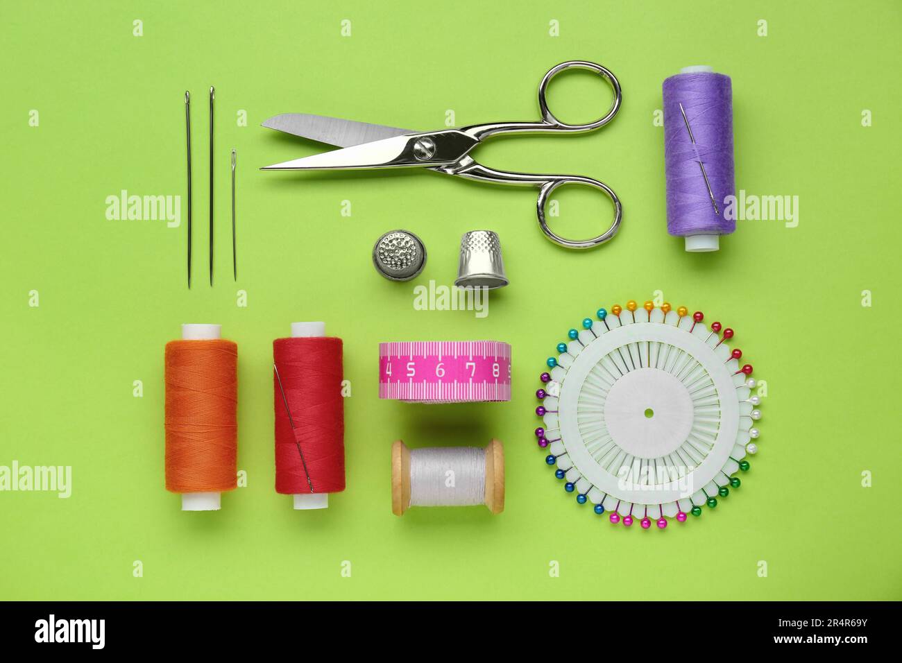 Flat lay composition with thimbles and different sewing tools on green ...