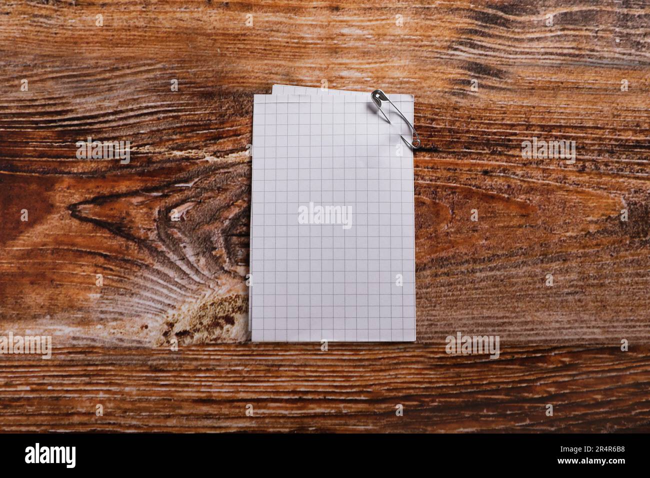 Paper sheets attached with safety pin on wooden table, top view. Space ...
