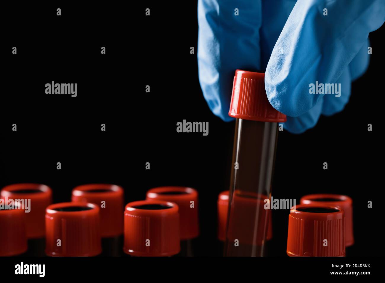 Scientist putting test tube with brown liquid into stand against black ...