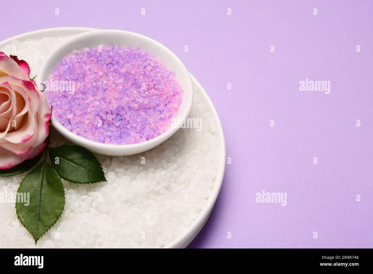 Aromatic sea salt and beautiful flower on purple background. Space for ...