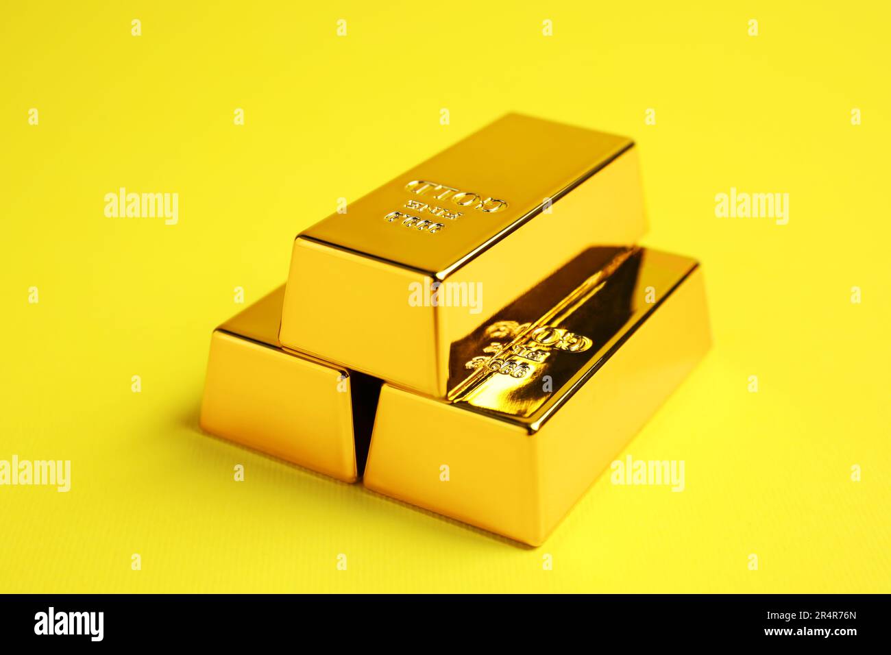 Stack of shiny gold bars on yellow background Stock Photo - Alamy