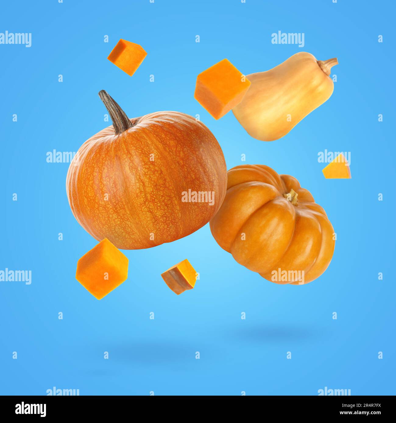 Whole and cut pumpkins falling on light blue background Stock Photo - Alamy