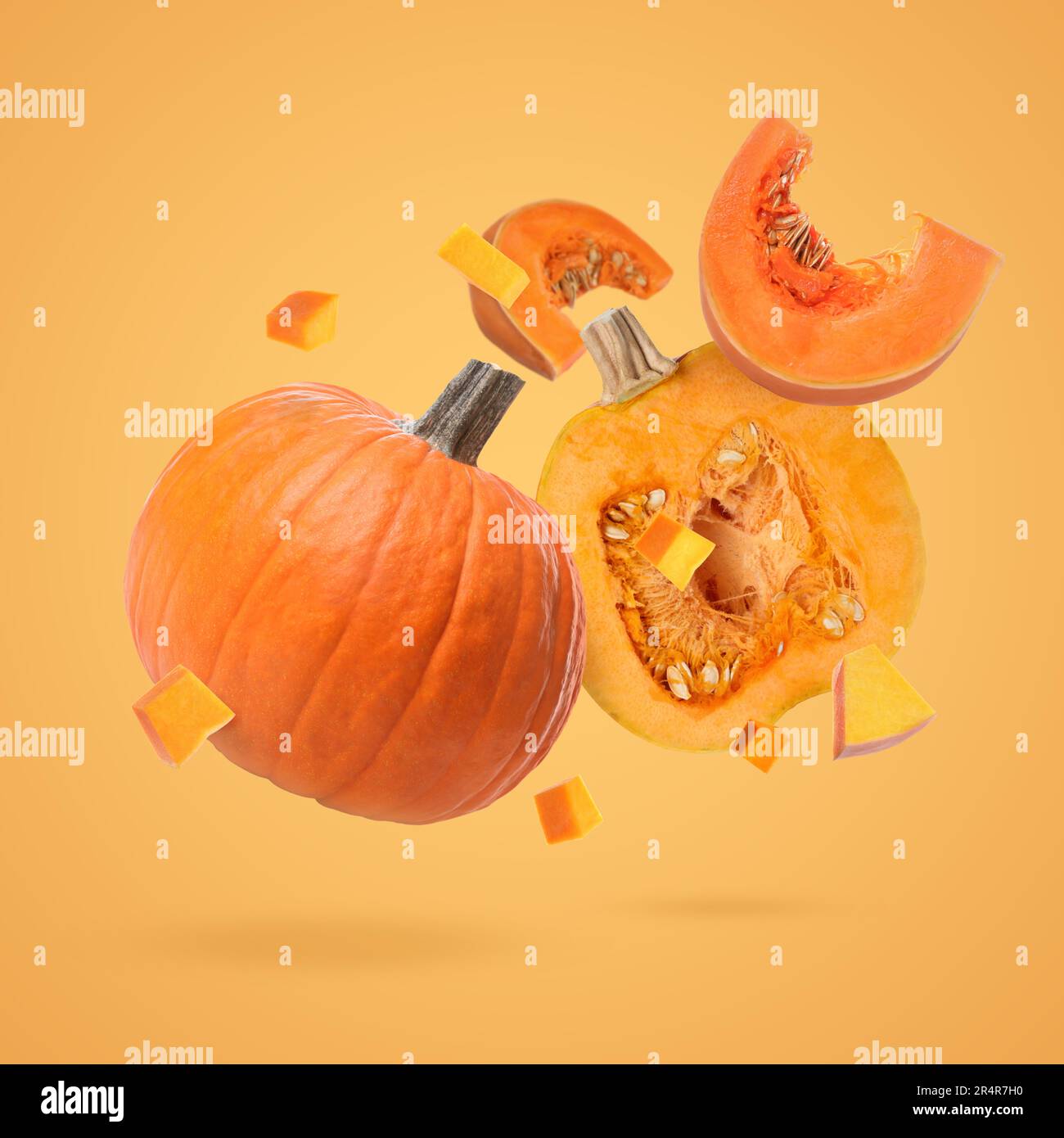 Whole and cut pumpkins falling on orange background Stock Photo - Alamy