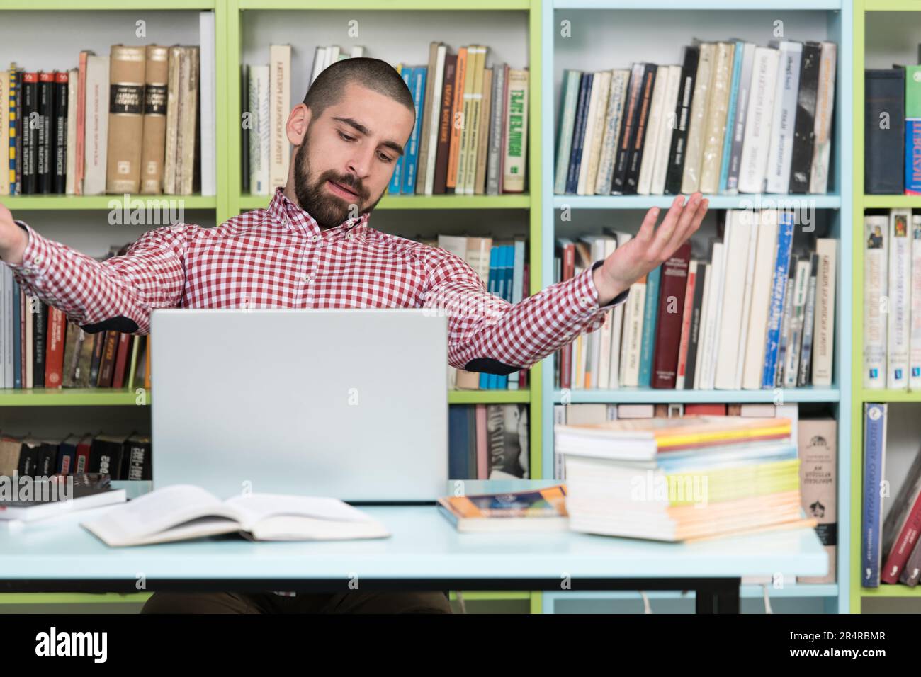 Stressed Young Male Student Reading Textbook While Sitting in Library ...