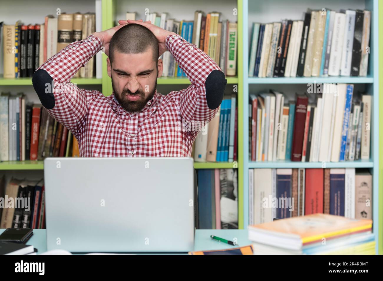 Stressed Young Male Student Reading Textbook While Sitting in Library ...