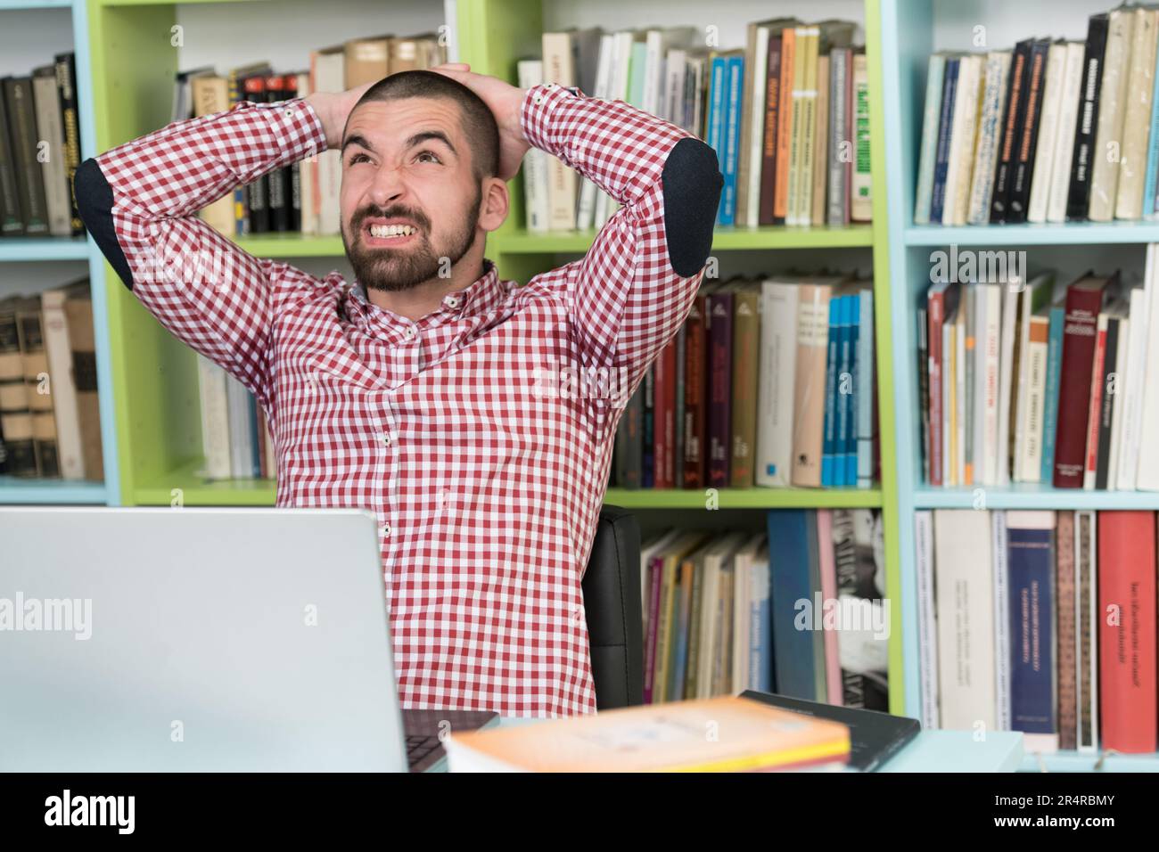 Stressed Young Male Student Reading Textbook While Sitting in Library ...