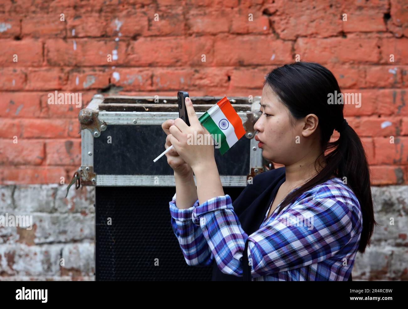 A woman belonging to Manipur 'Kuki tribe' holds takes a photo while ...