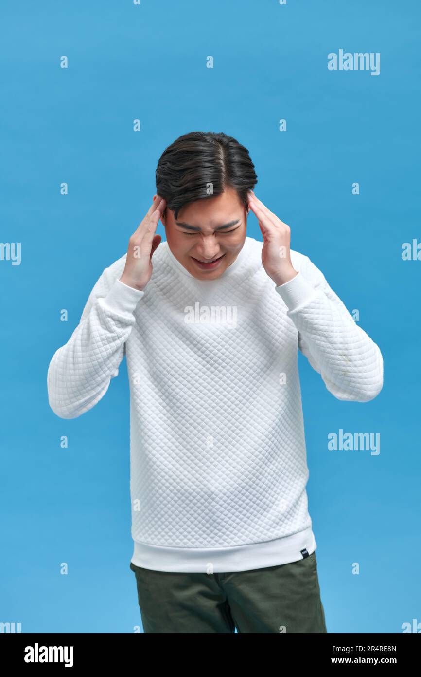 Young Asian man touching head temples experiencing stress having ...