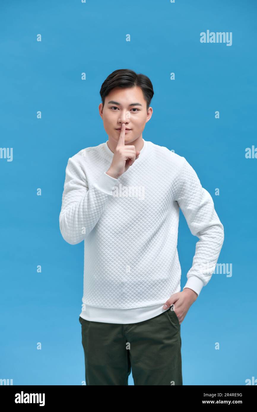 Asian handsome young man holding index finger on lips asking for ...